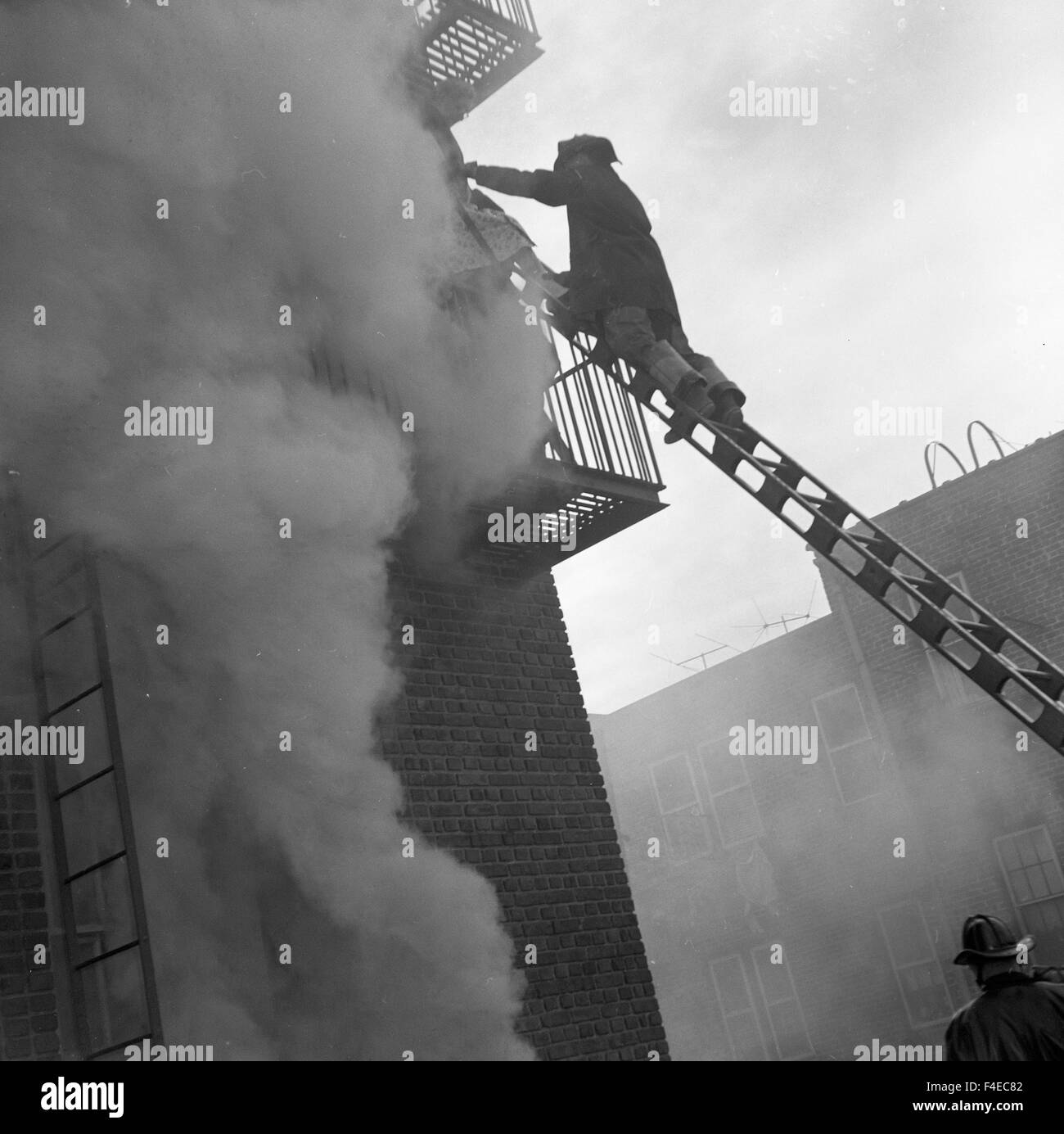 firefighter going up a ladder to a smoke filled apartment to make ...