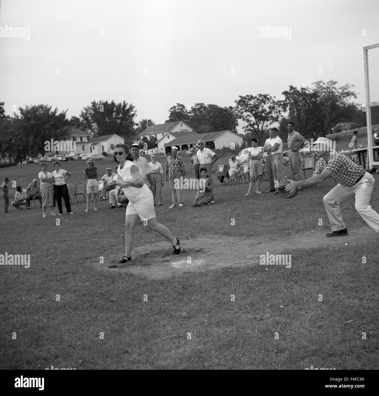 playing baseball in a frield man catching and woman running to 1st base ...