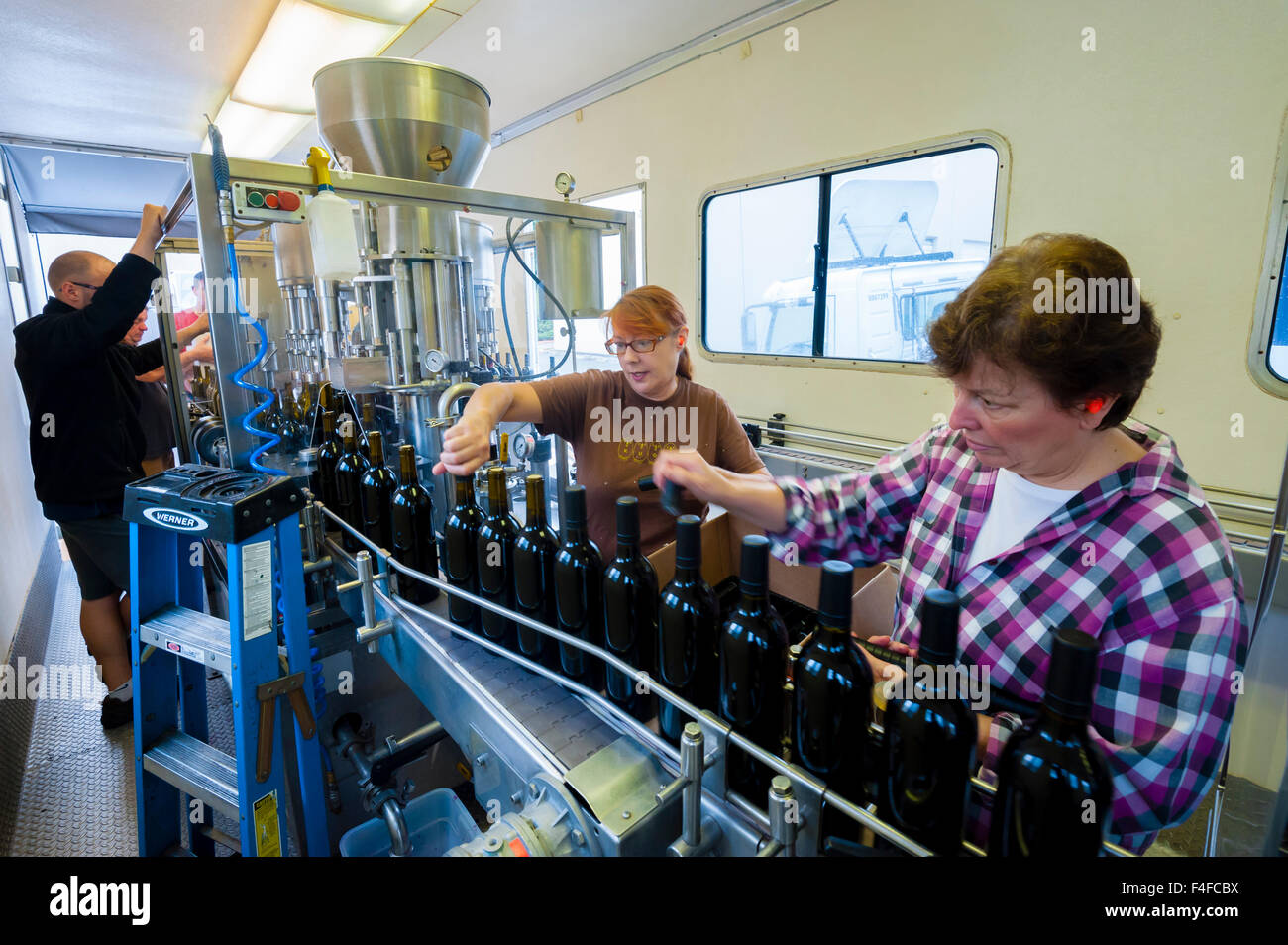 USA, Washington, Woodinville. Winery crews work the bottling line of ...