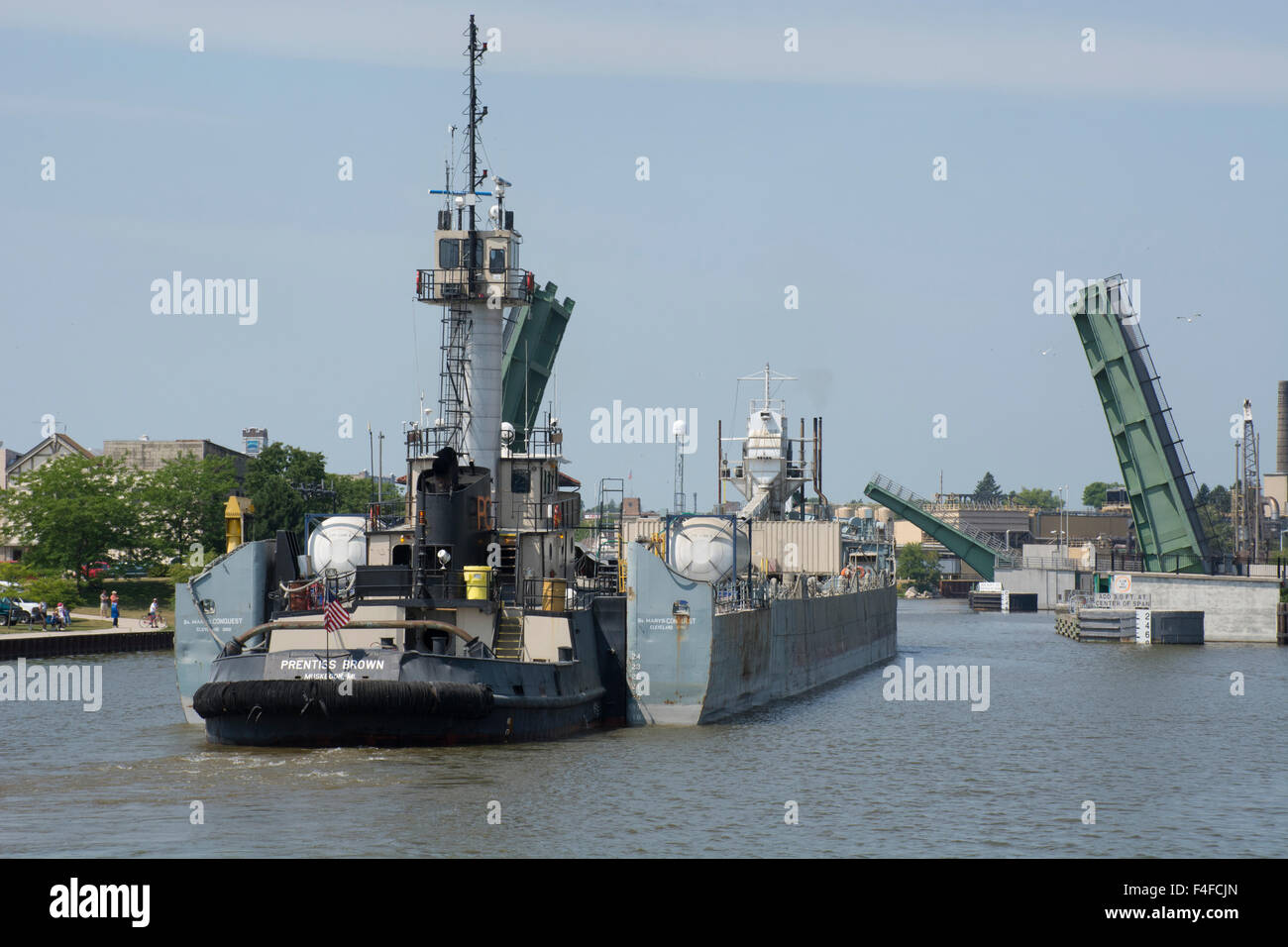 Wisconsin, Manitowoc. Manitowoc River. Tugboat pushing barge sailing up ...
