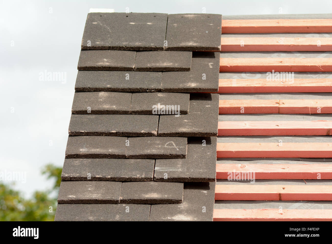 Rows of roof tiles being fitted to wooden battens on Victorian style ...