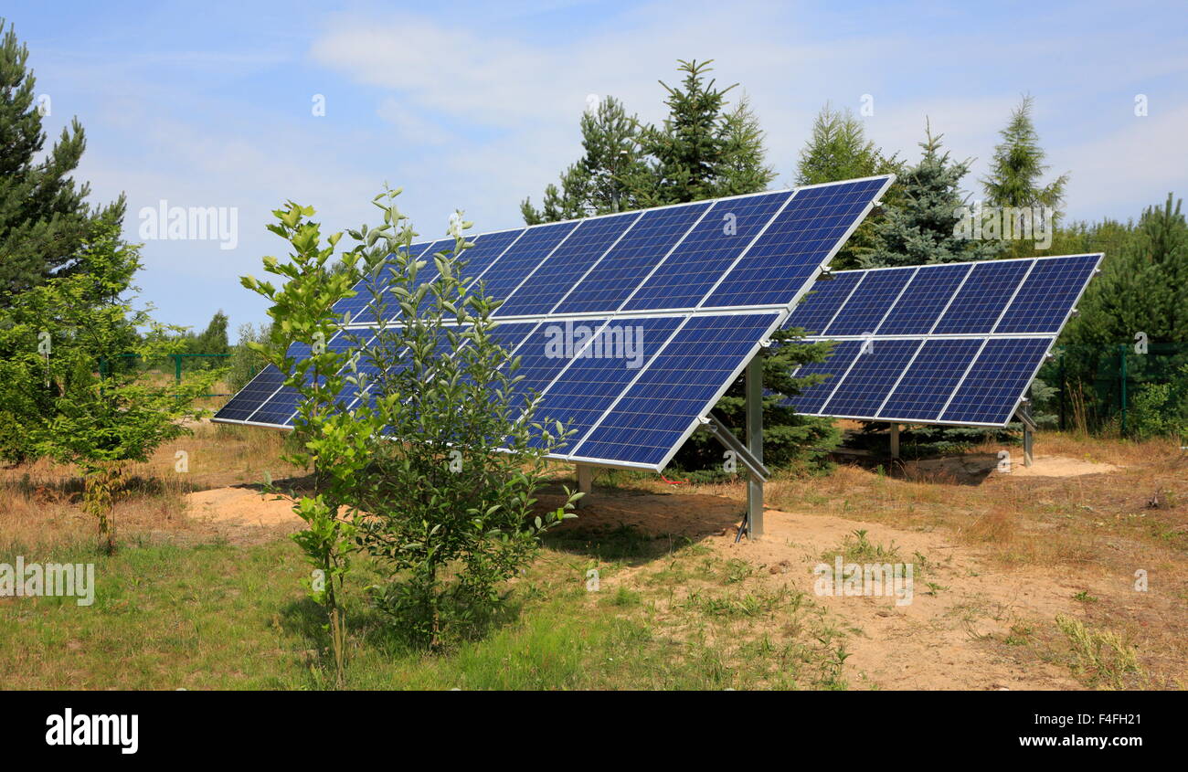 Two photovoltaic panels set in backyard against trees and blue sky ...
