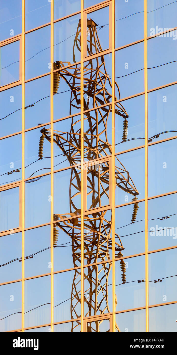 High voltage electric tower is reflected in the mirrored windows of the ...