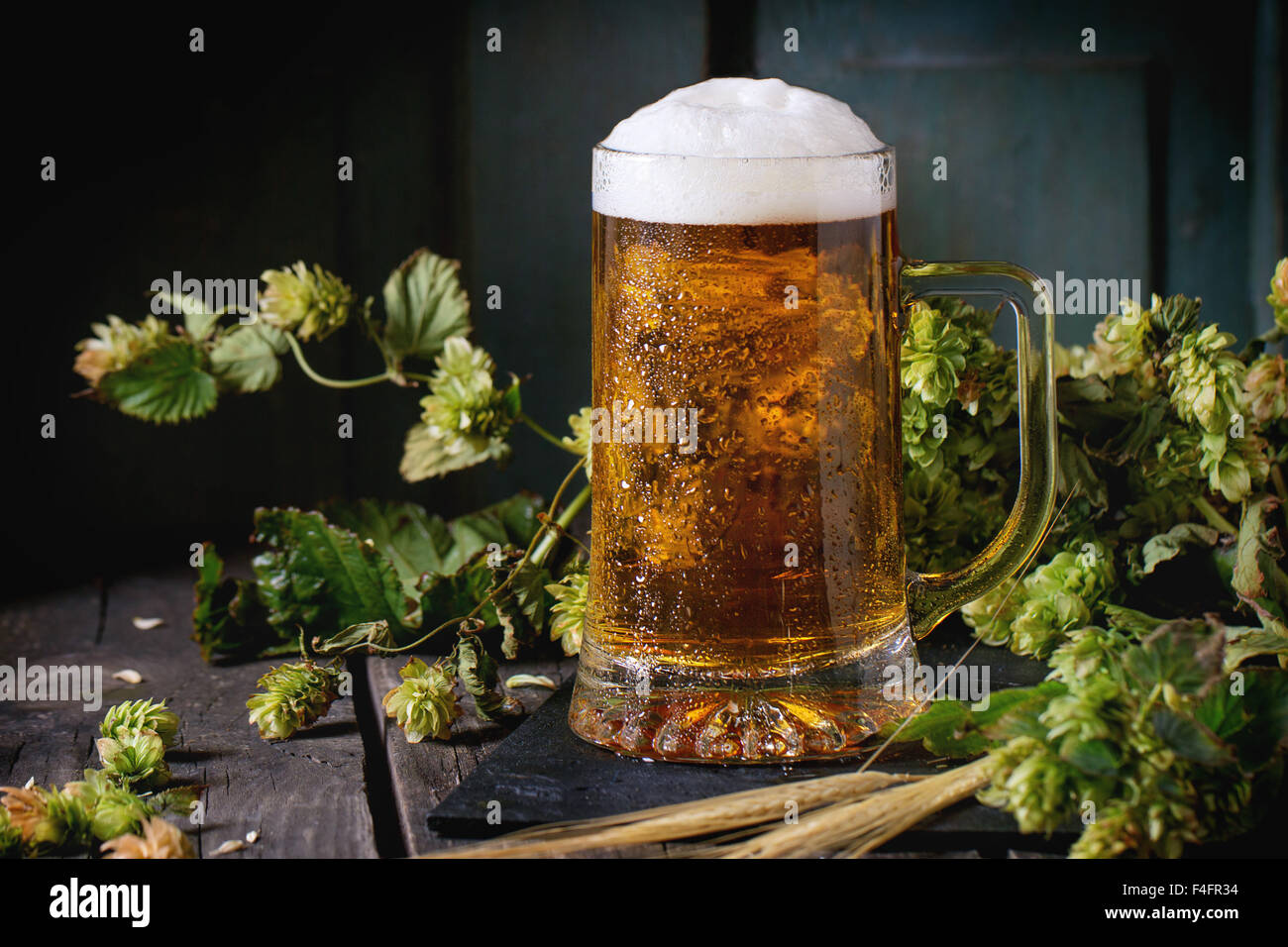 Mug of fresh draught lager beer with foam on black slate, served on old ...