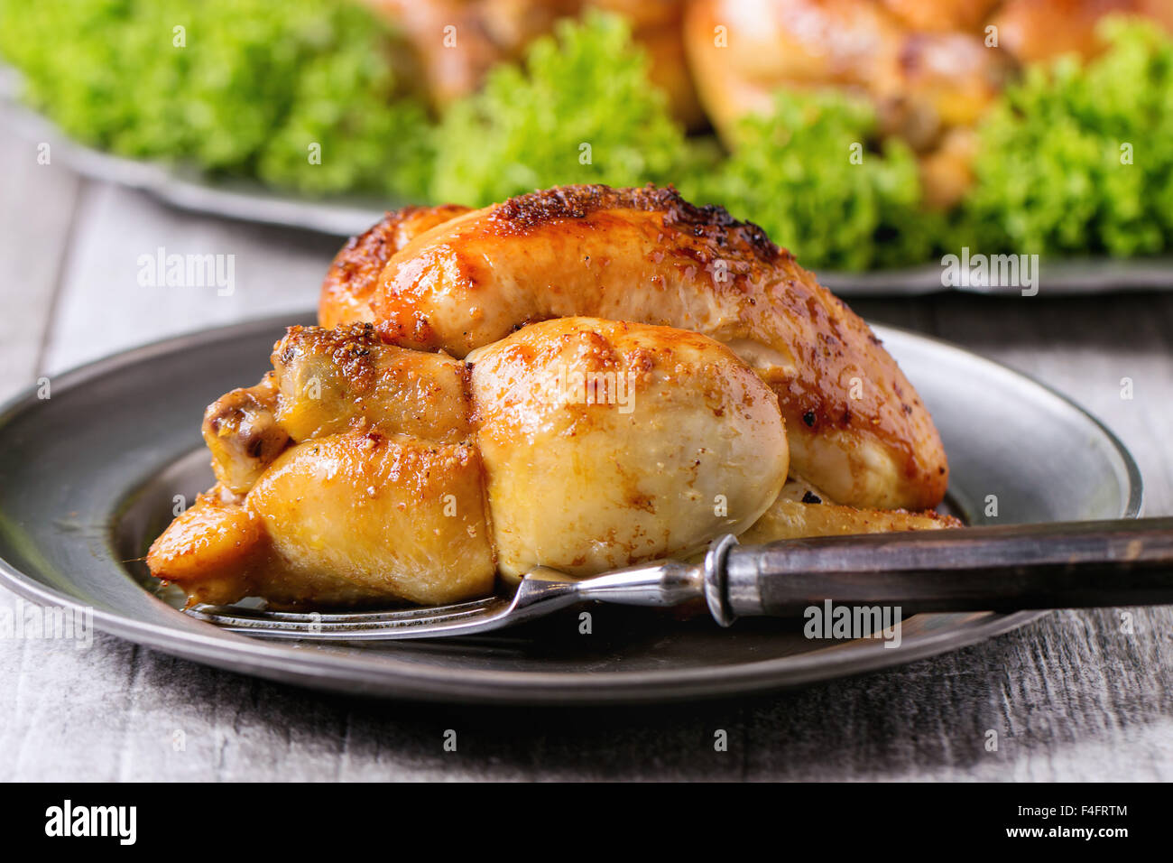 Whole Grilled mini chicken on vintage metal plate and dish with chicken ...