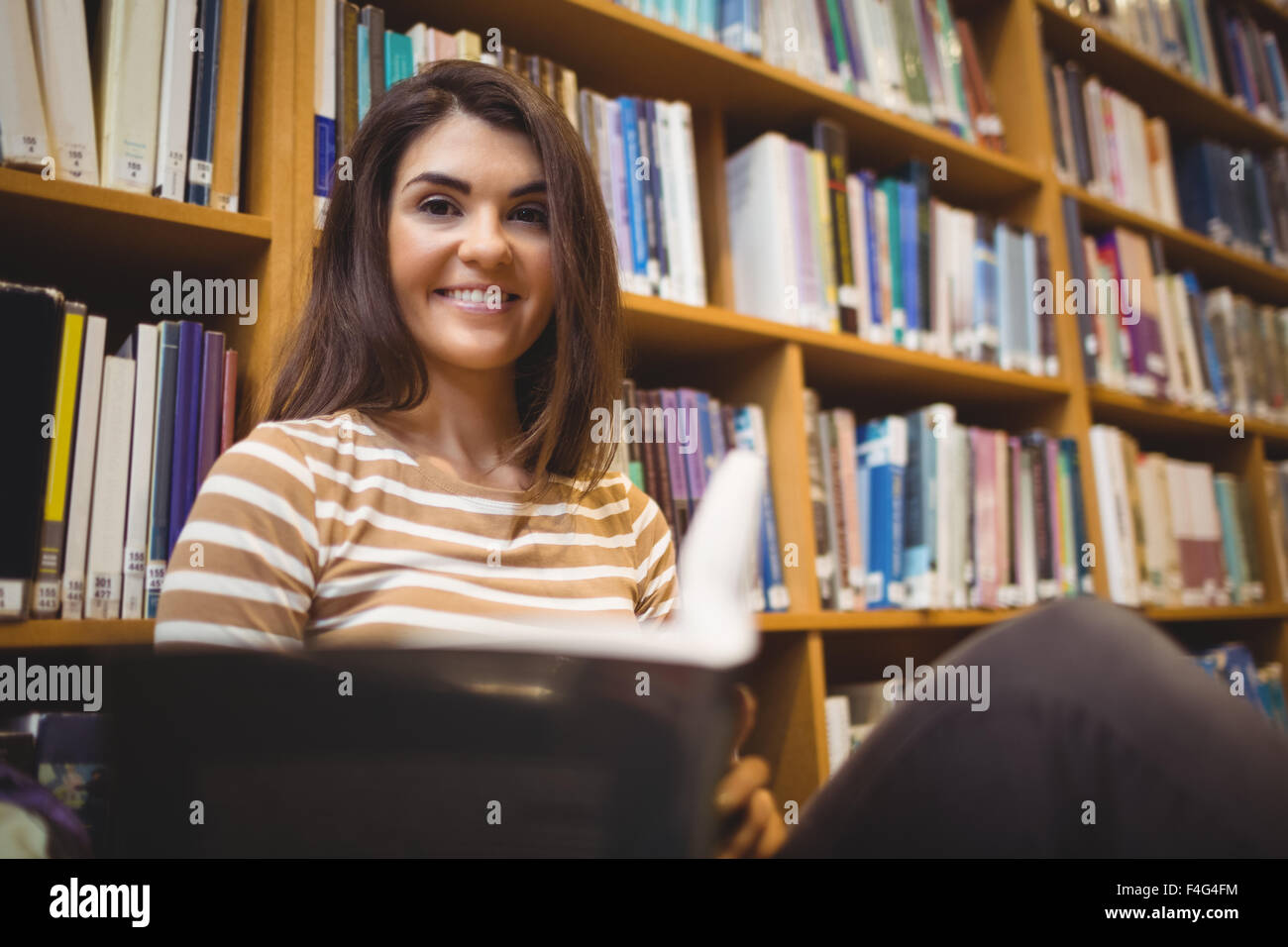 Portrait of cheerful student sitting in library Stock Photo - Alamy