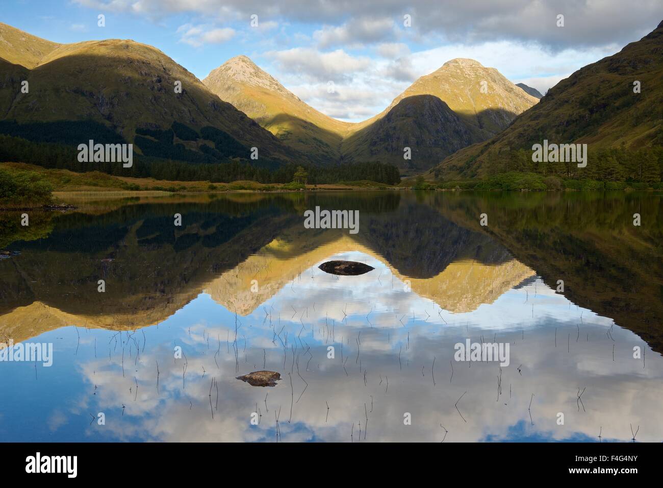 Golden light from the dipping sun hits the banks of a still Lochan Urr ...