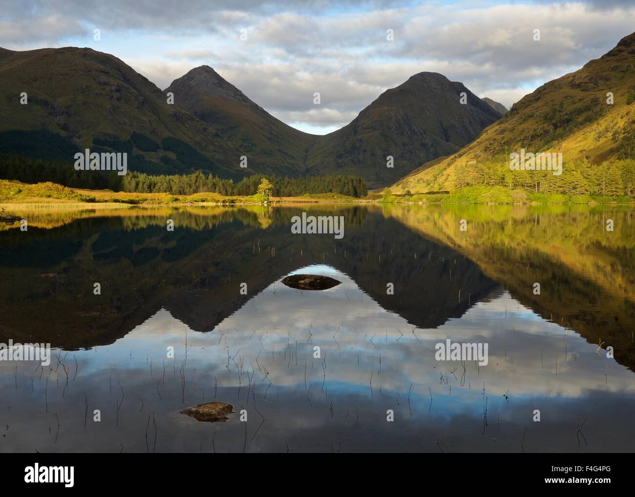 Golden light from the dipping sun hits the banks of a still Lochan Urr ...