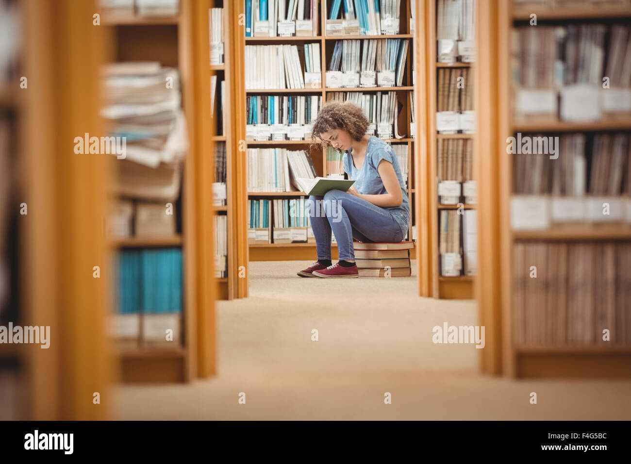 Pretty student in library sitting on the floor Stock Photo - Alamy