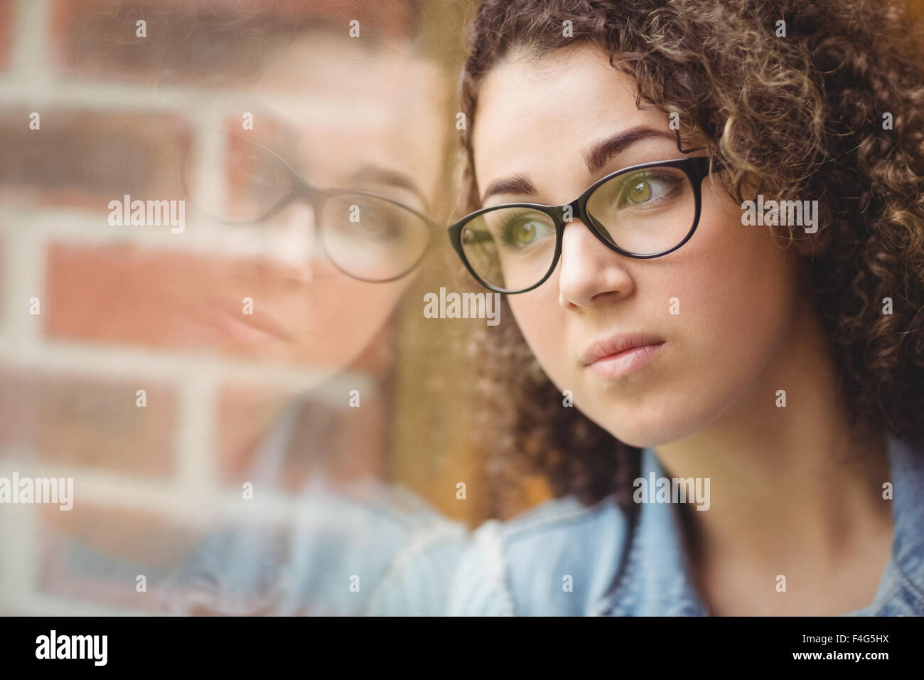 Pretty student sitting by window thinking Stock Photo - Alamy