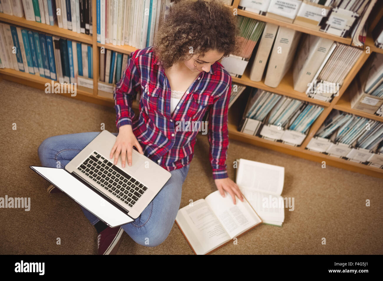 Pretty student in library using laptop Stock Photo - Alamy