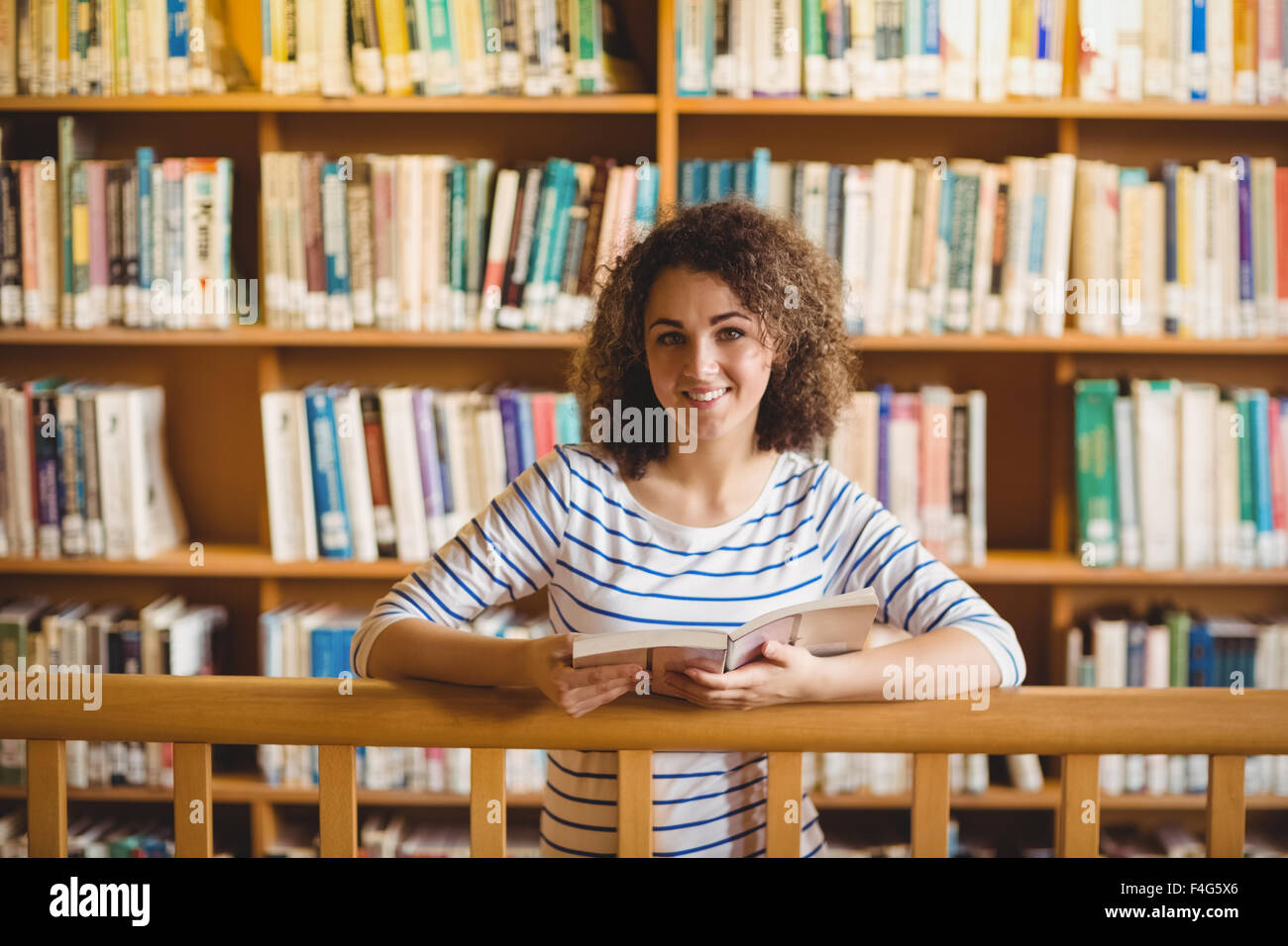 Pretty student in library reading book Stock Photo - Alamy