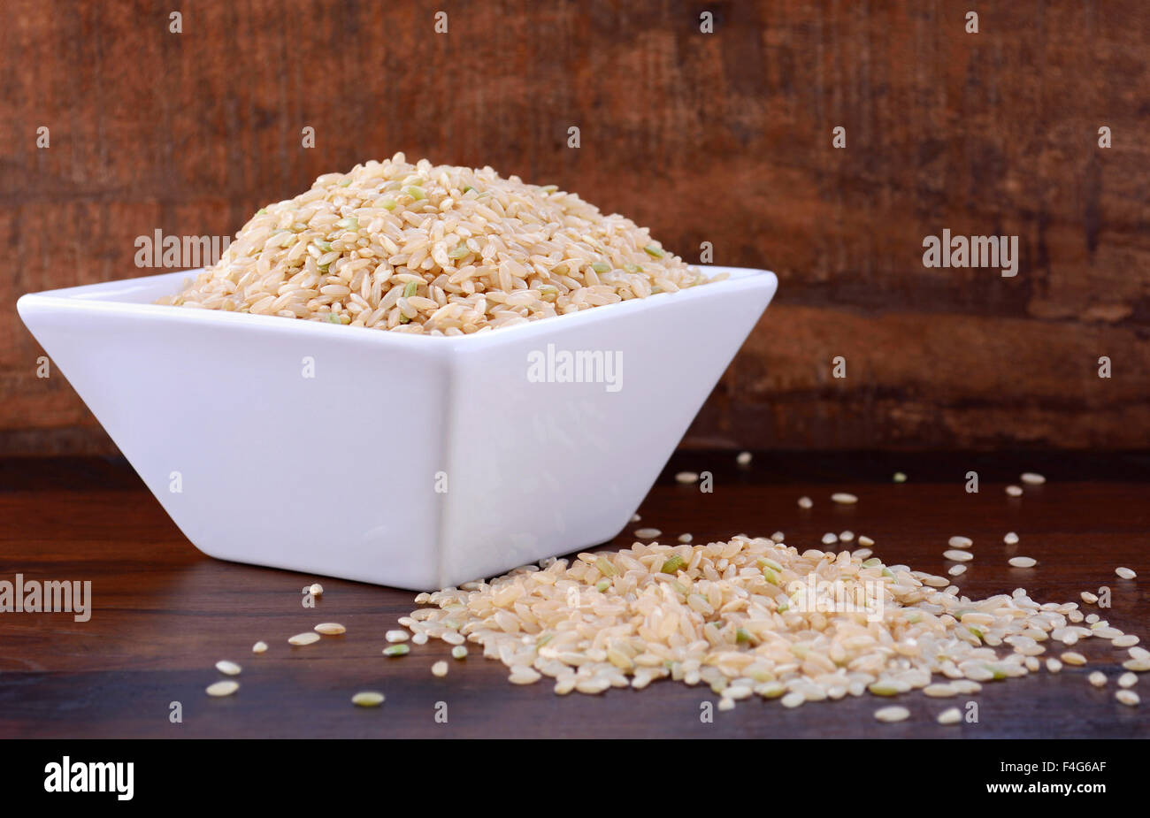 Square bowl of uncooked brown rice on dark wood vintage background ...