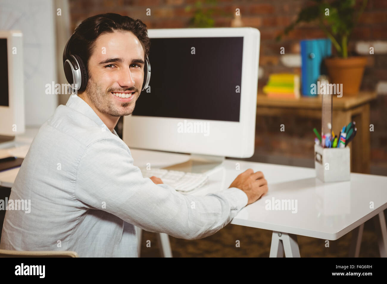 Smiling man using headphones at office desk Stock Photo - Alamy