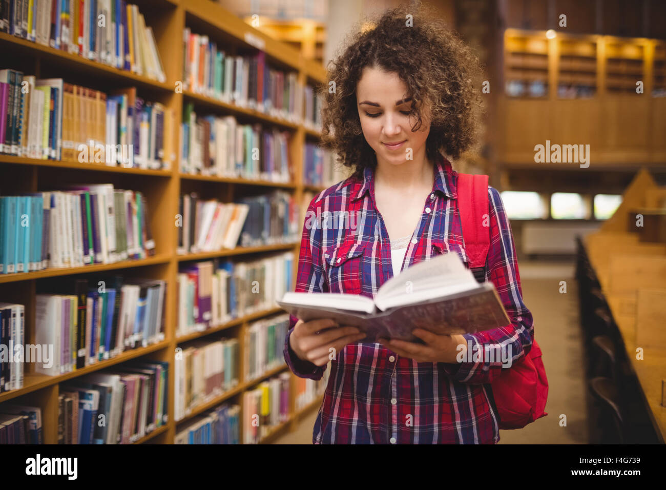 Pretty student in the library reading book Stock Photo - Alamy