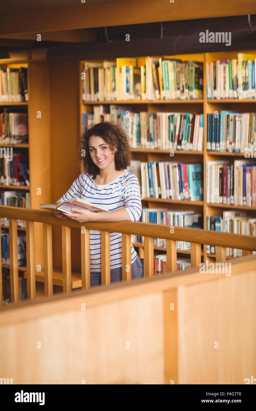 Pretty student in library reading book Stock Photo - Alamy