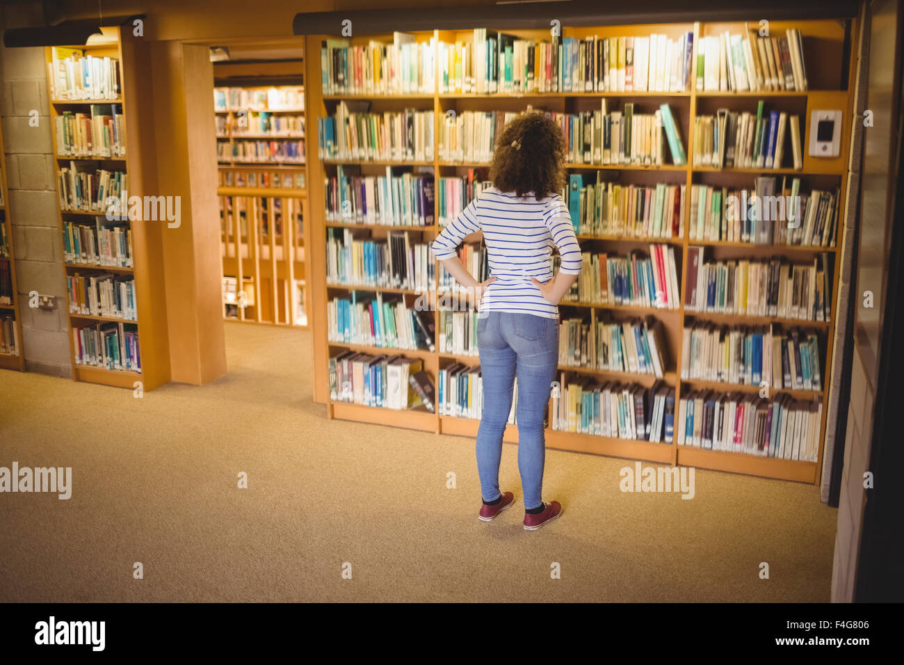 Pretty student in library choosing book Stock Photo - Alamy