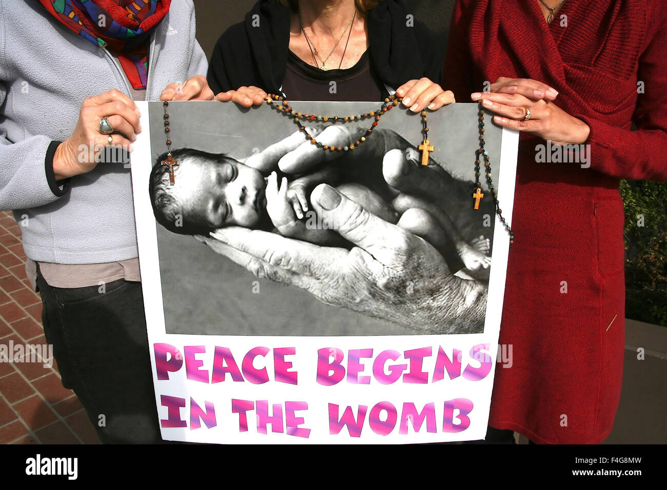 Pro-life poster adorned with crucifixes held by mothers outside an ...