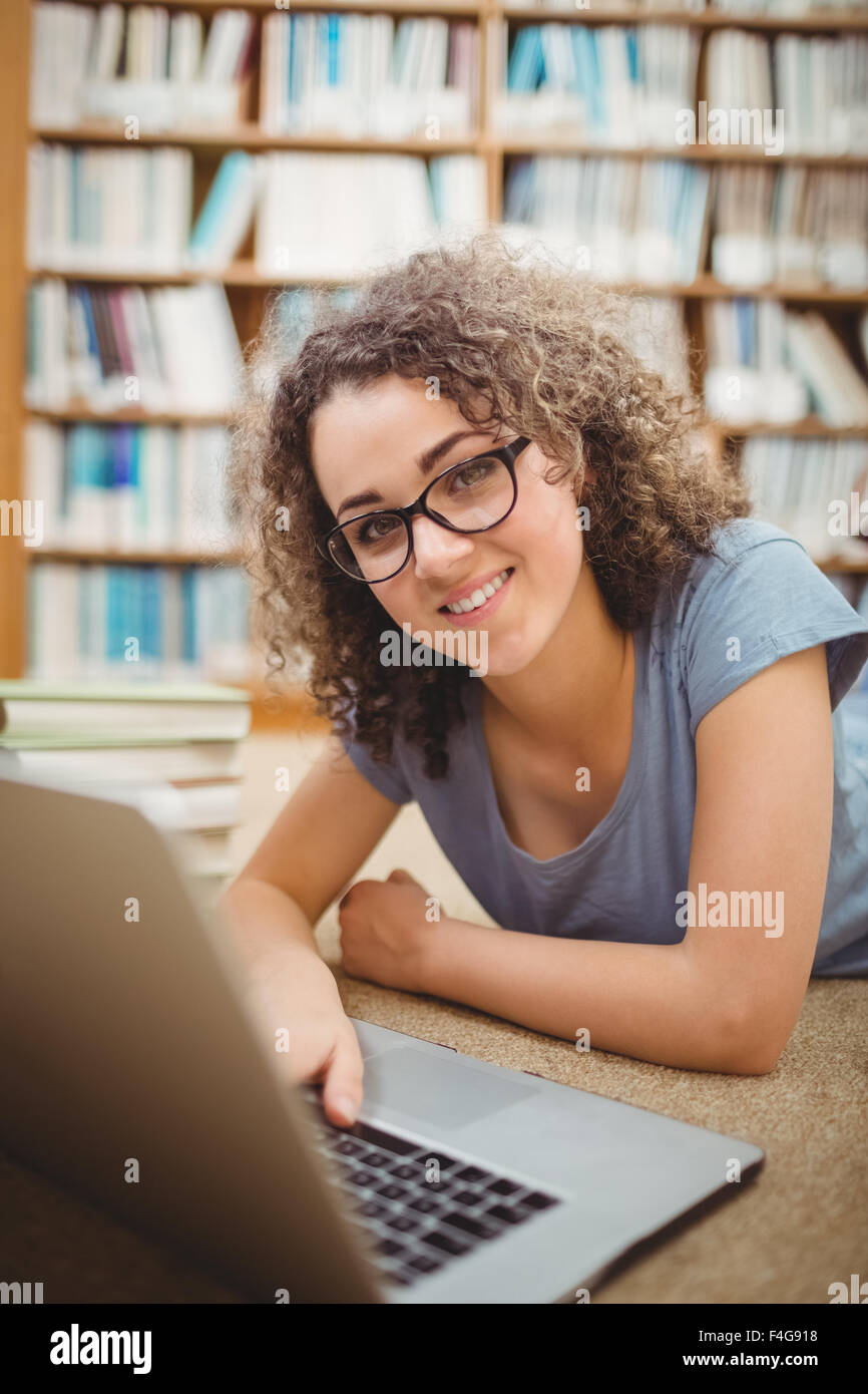 Pretty student in library using laptop Stock Photo - Alamy