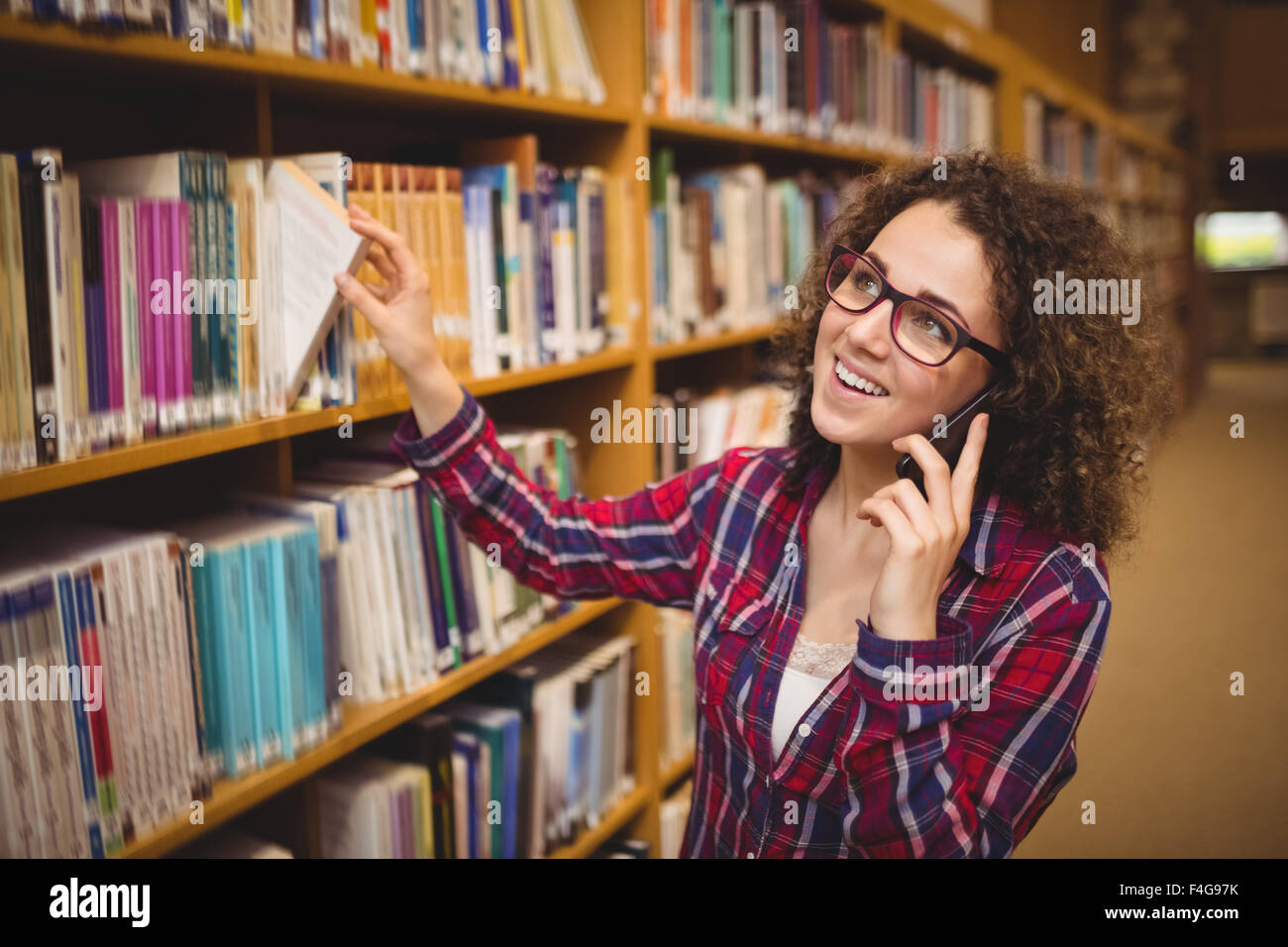 Pretty student in the library taking book Stock Photo - Alamy