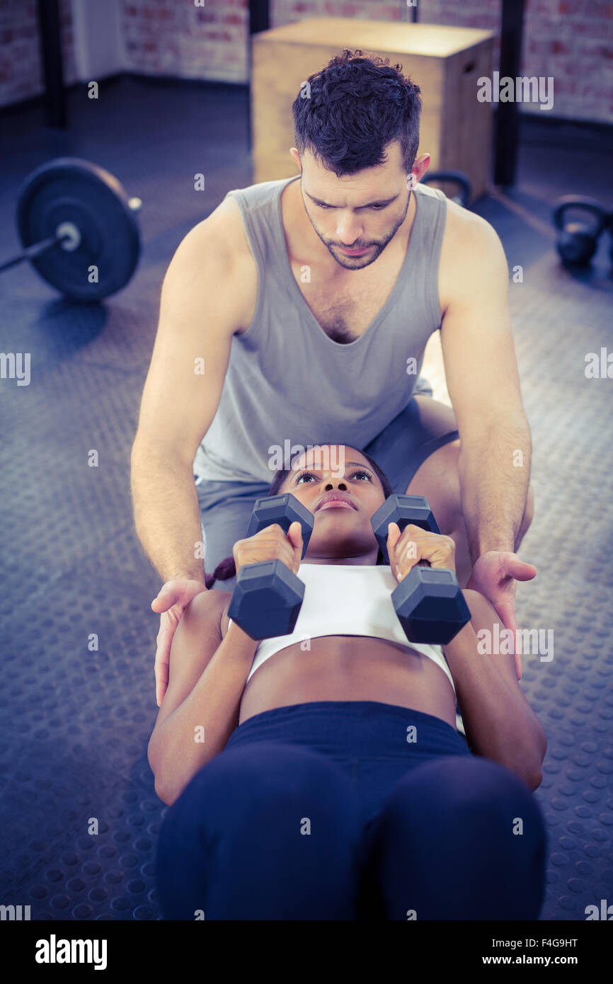 Personal trainer working with client holding dumbbell Stock Photo - Alamy