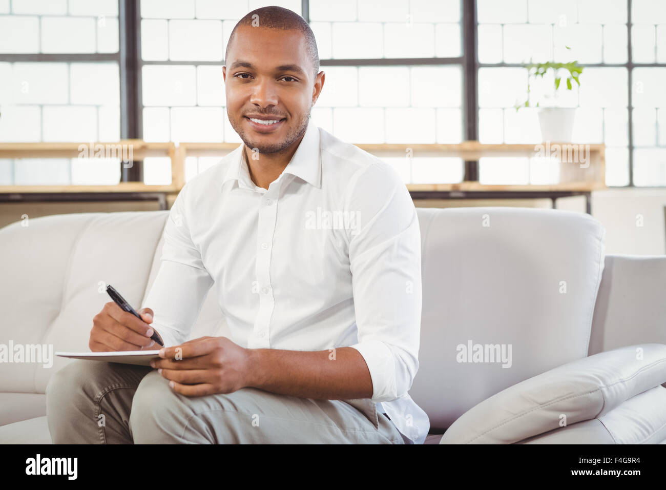 Smiling therapist writing on book at clinic Stock Photo - Alamy