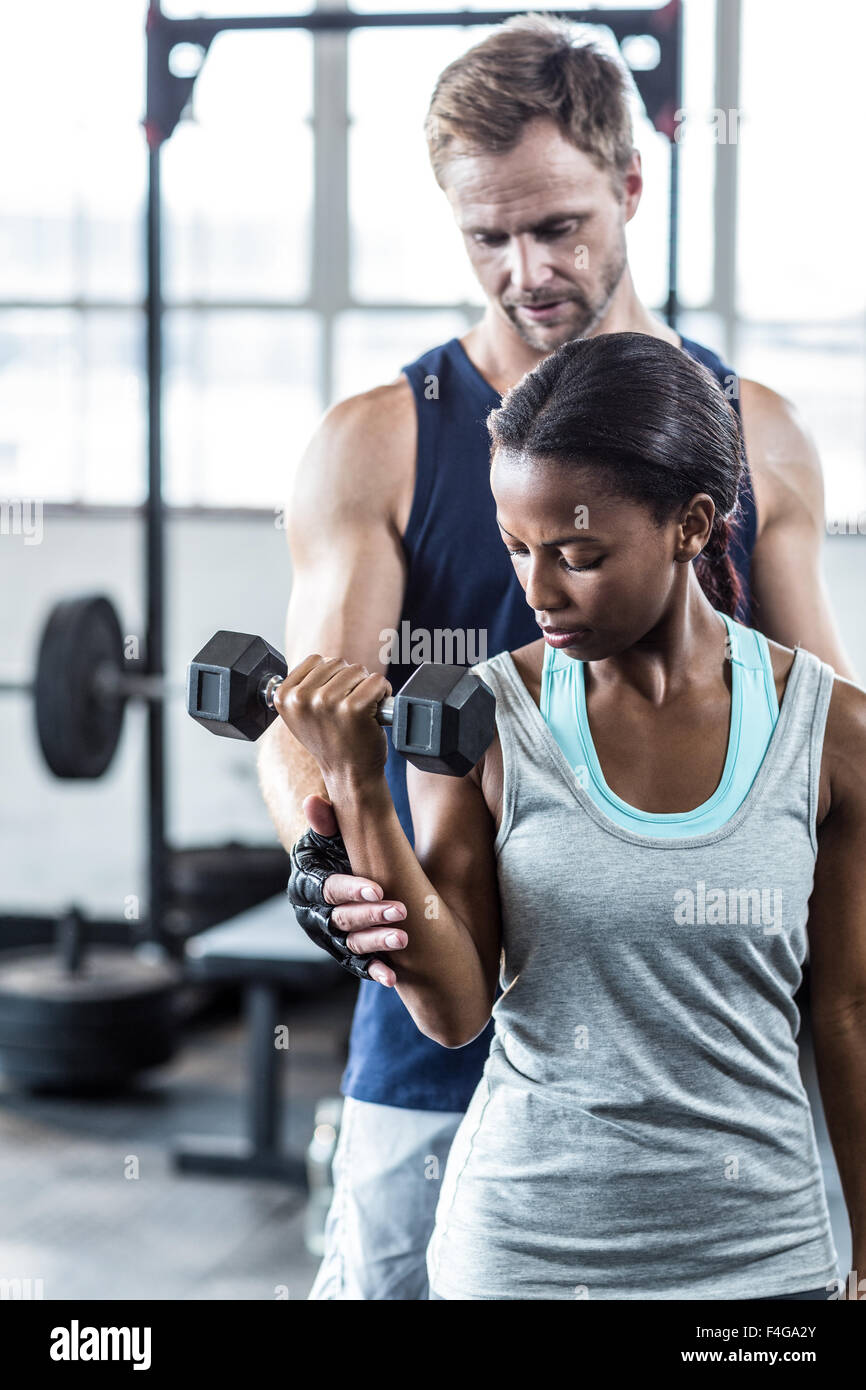 Male trainer assisting woman with dumbbell Stock Photo - Alamy