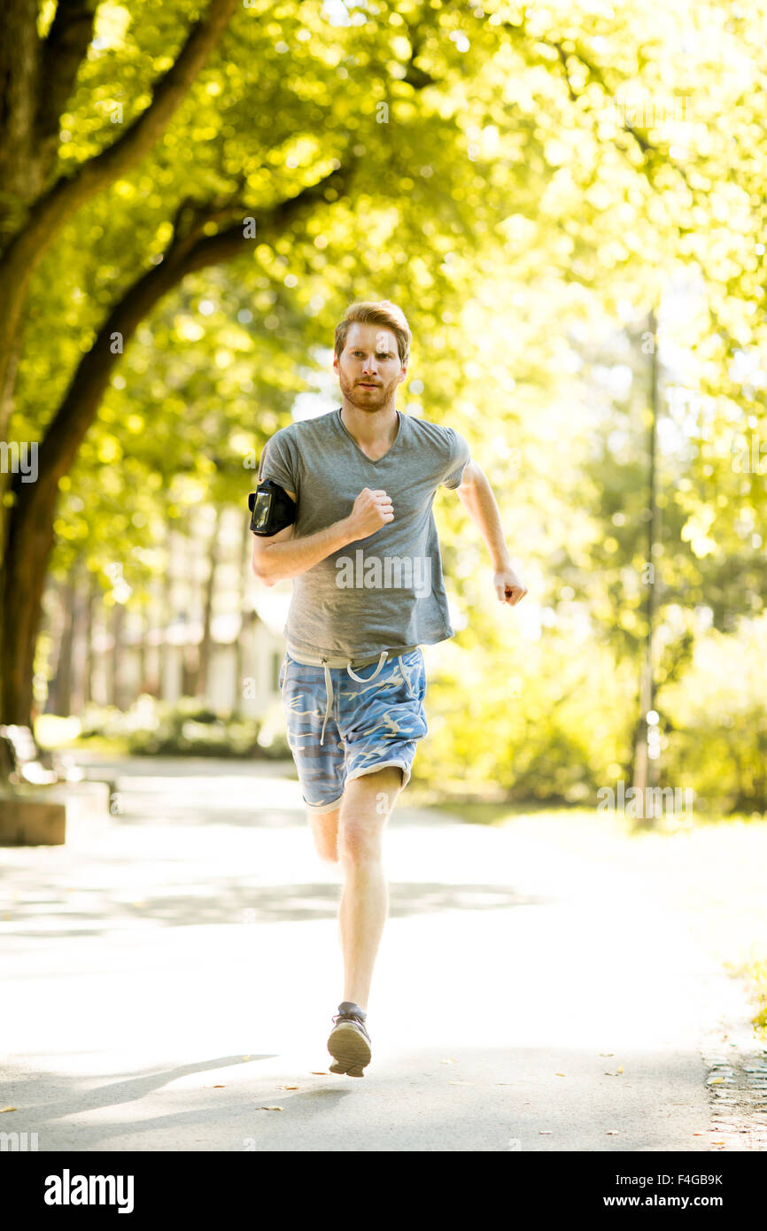 Young man running in the autumn park Stock Photo - Alamy