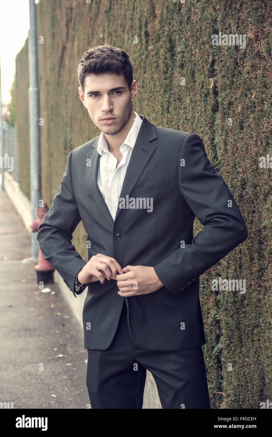 Handsome young man in elegant business suit standing outdoor in street ...