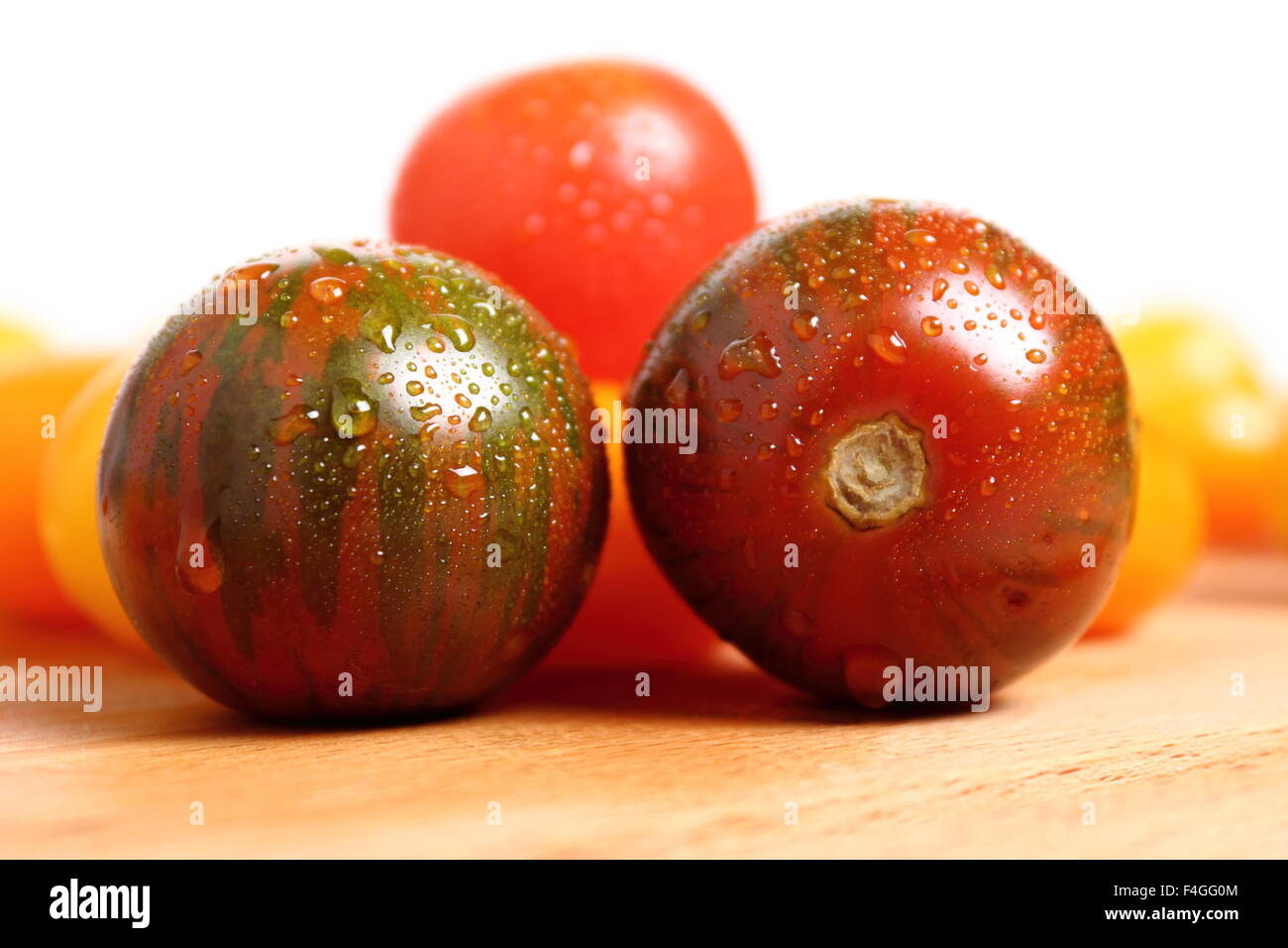 Black zebra tomatoes with drops on wooden surface. Macro. White ...