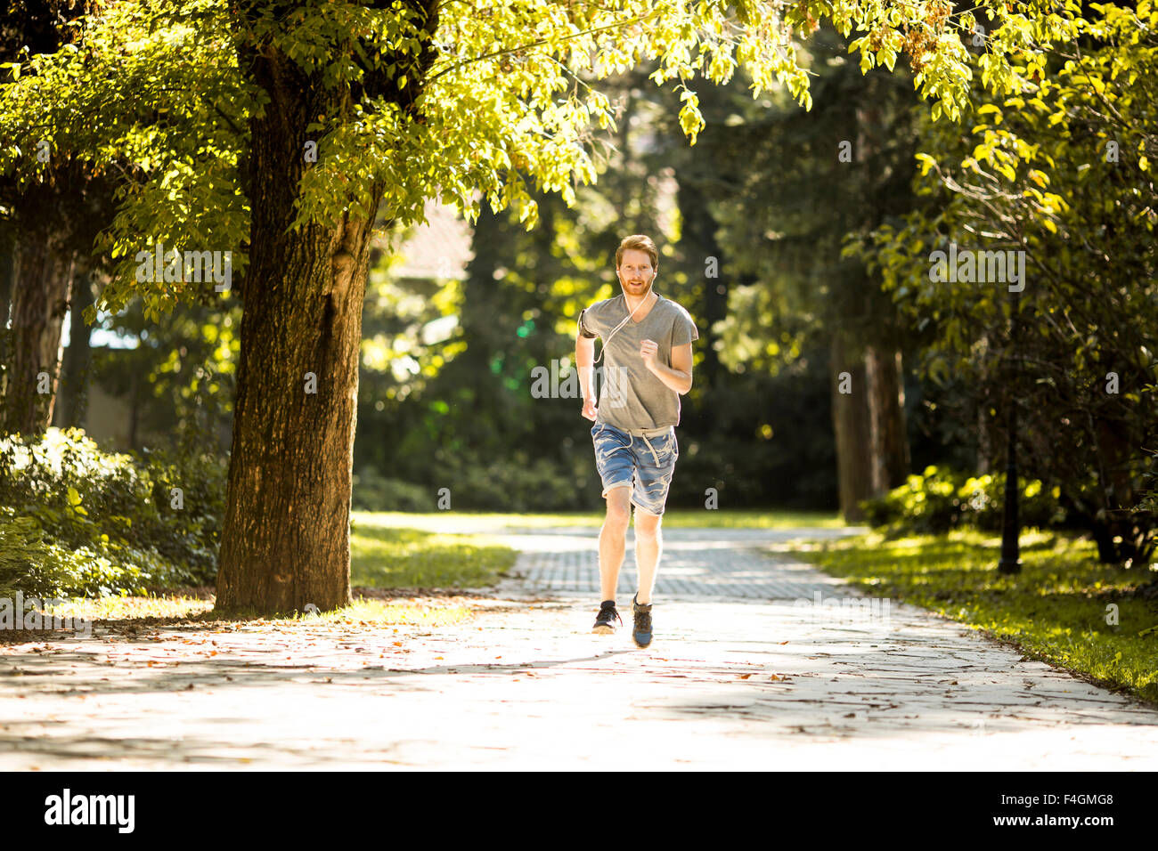 Young man running in the autumn park Stock Photo - Alamy