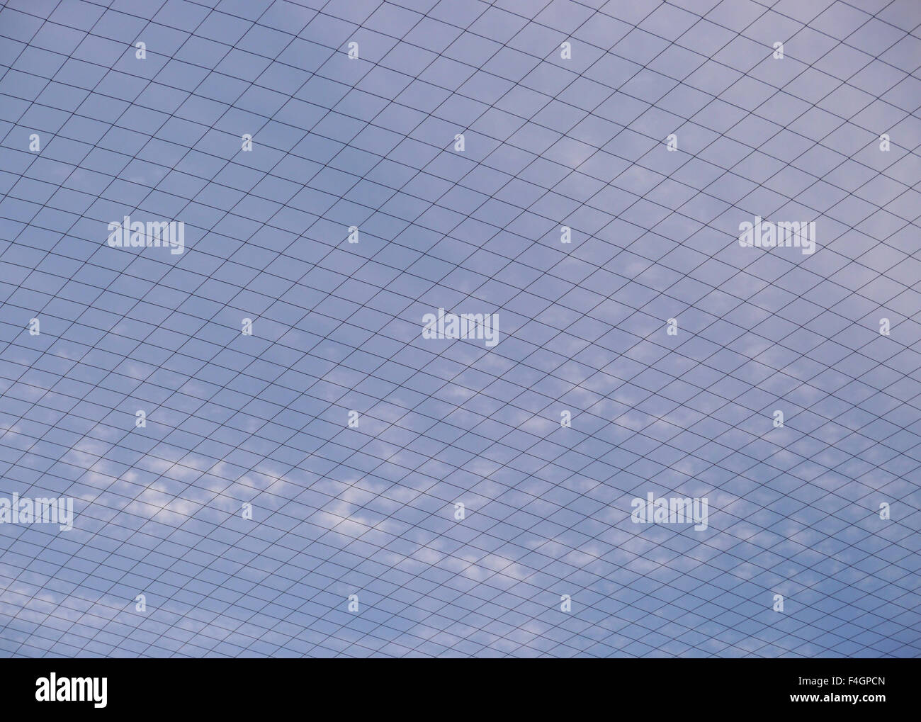 A blue sky with white clouds through a fine square mesh netting Stock ...