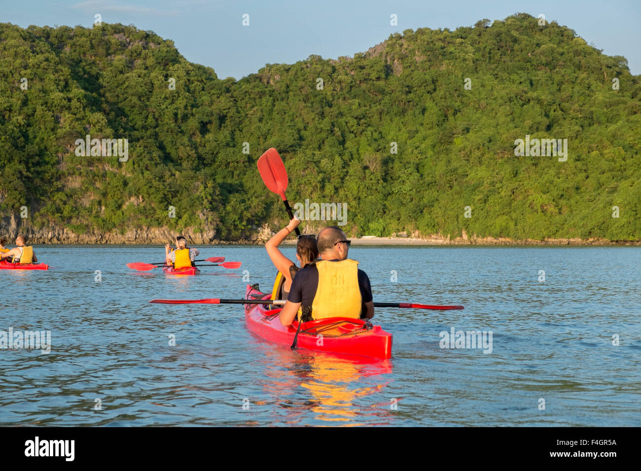 Tourists paddle in kayaks in the waters of Cong Do, part of Ha long bay ...