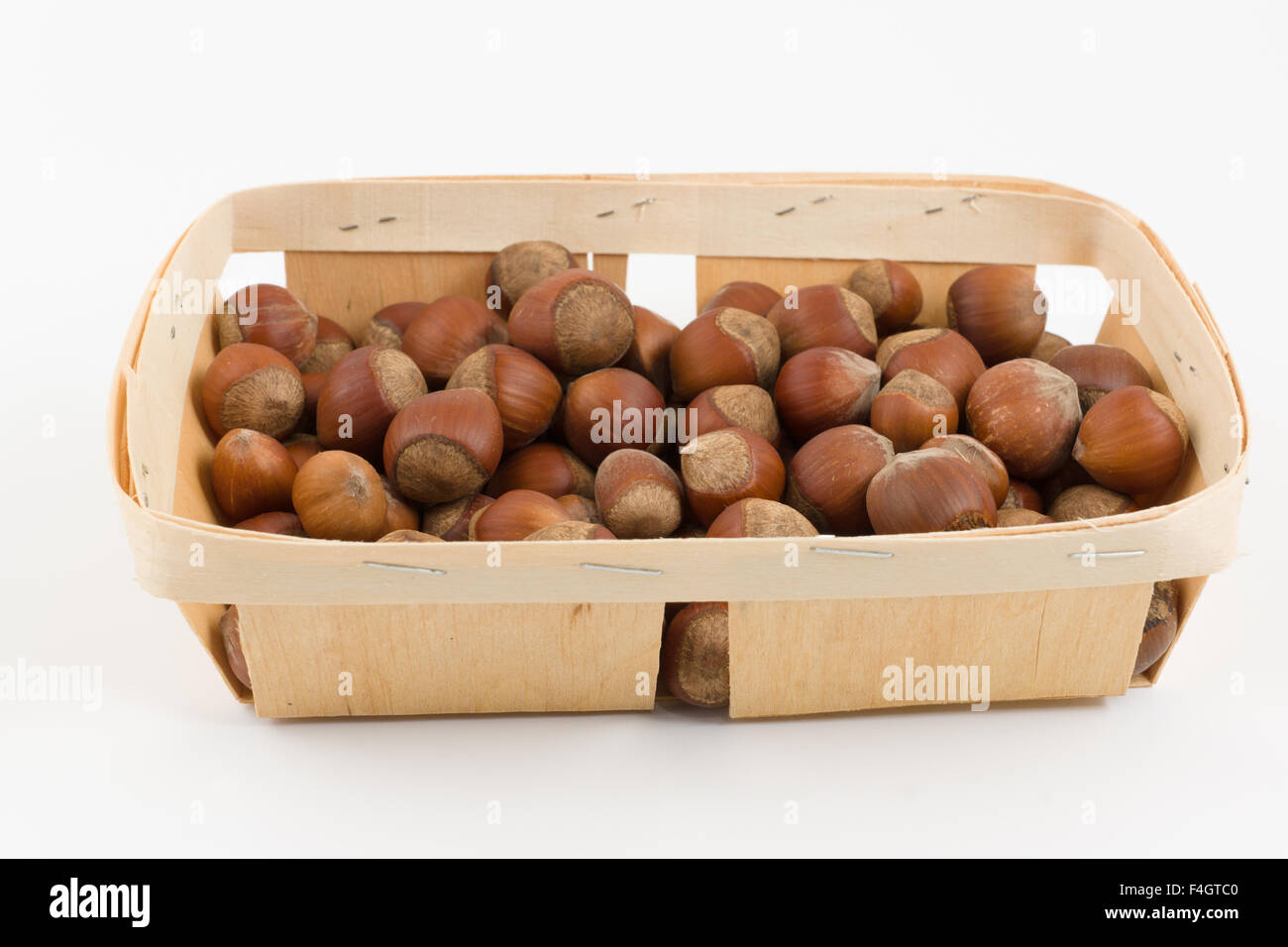 the wooden container is filled with hazelnut on a white background ...