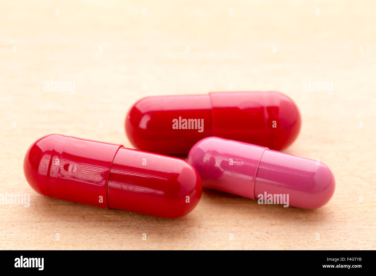 Three red capsules on the wooden table.Macro Stock Photo - Alamy