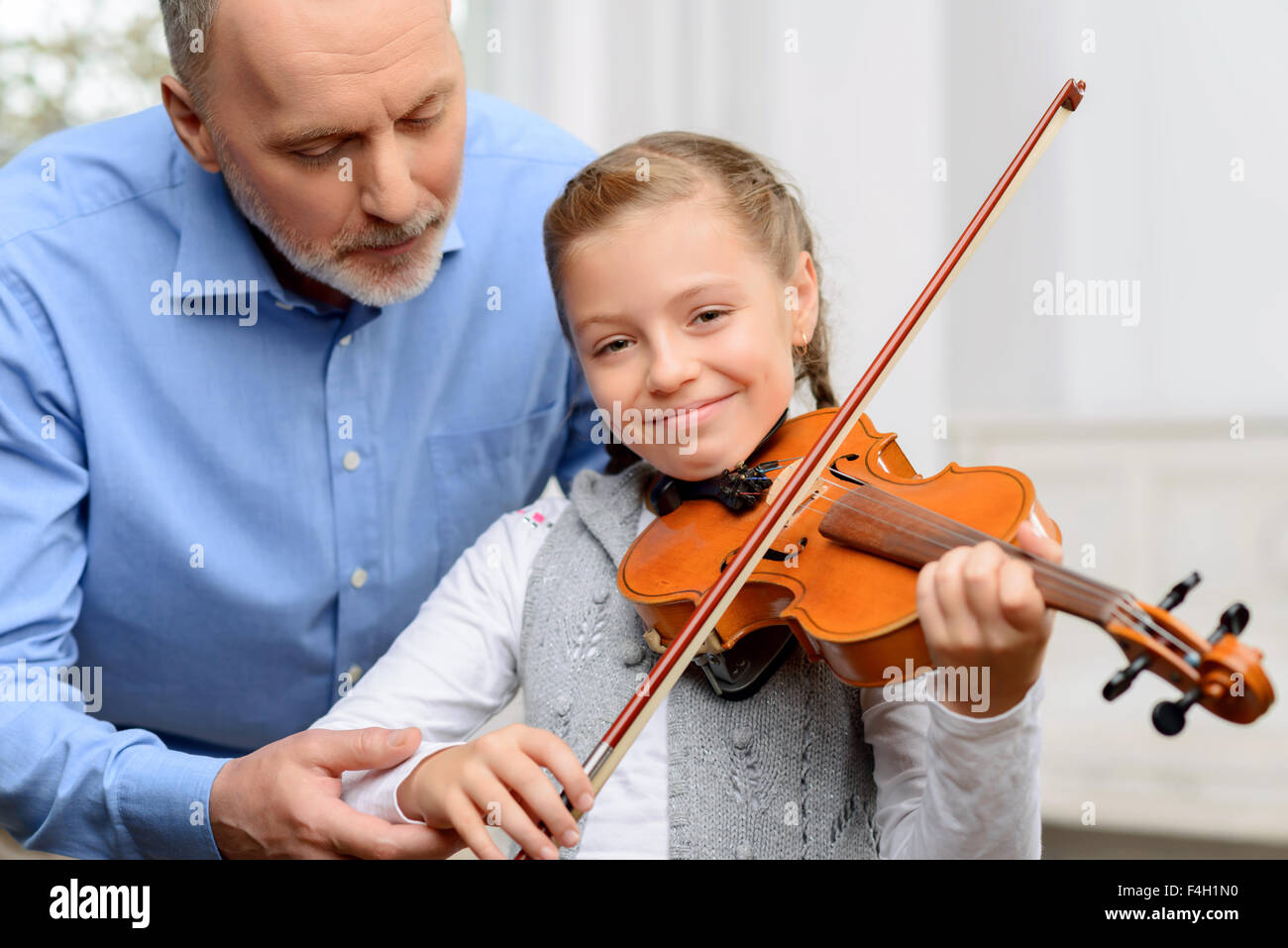 Enjoy music. Cheerful smiling little girl holding fiddle bow while ...