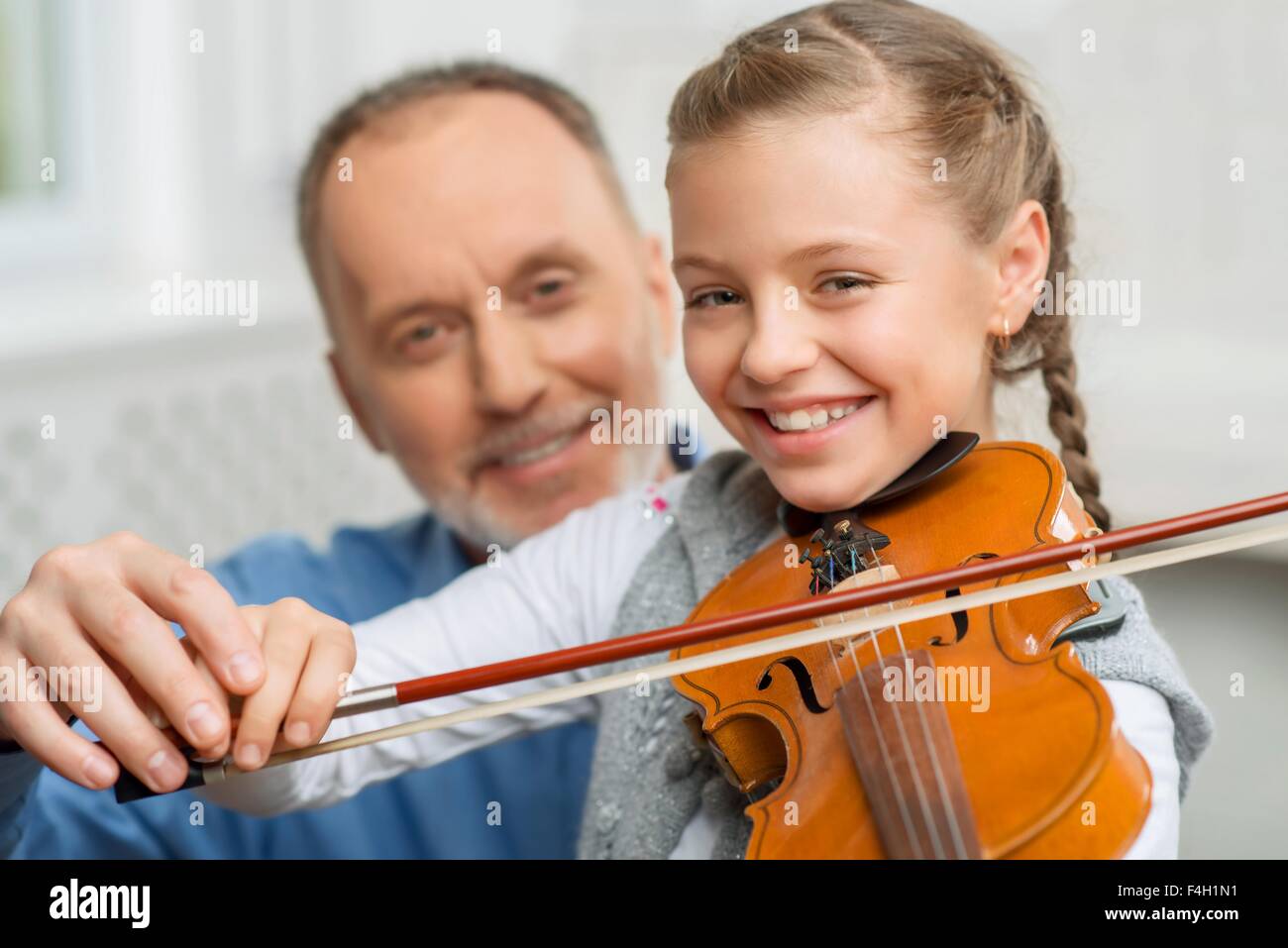 Best player. Vivacious pretty delighted little girl holding fiddle bow ...
