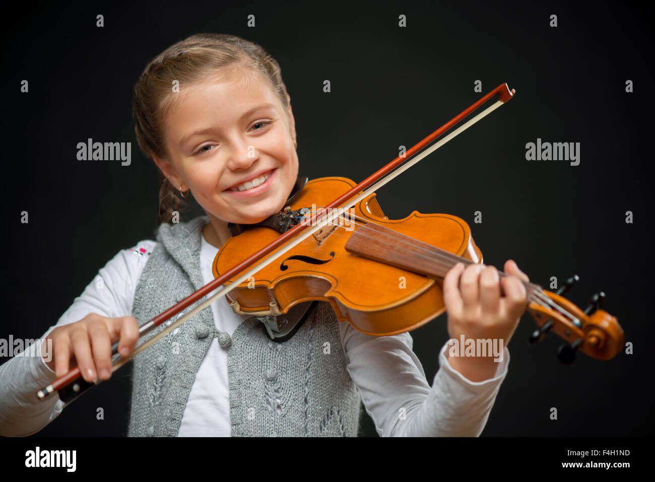 Nice player. Upbeat content little smiling girl holding fiddle bow and ...