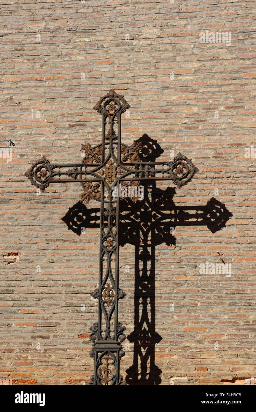Decorative iron cross and shadow on the brick wall of Pamiers Cathedral ...
