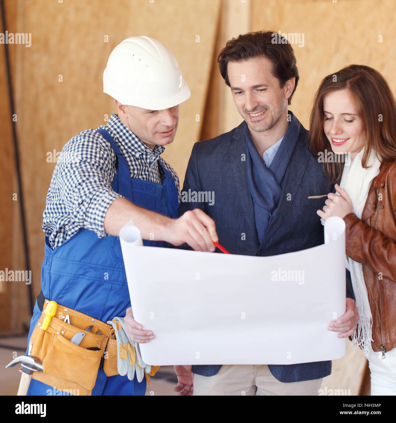 Construction: Young Couple Look At Home Plans with Builder Stock Photo ...