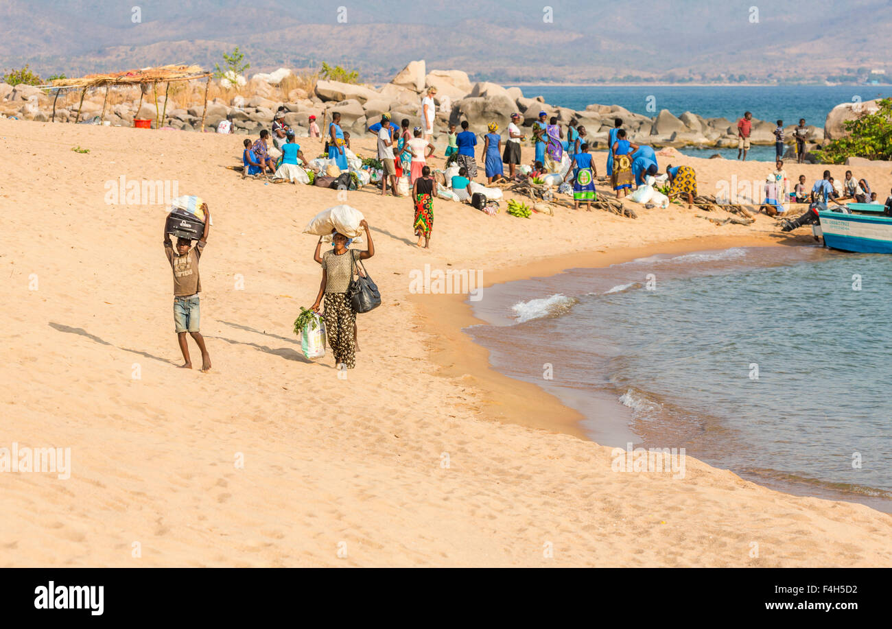 Local people unloading goods from a boat on the lakeside beach, Likoma ...