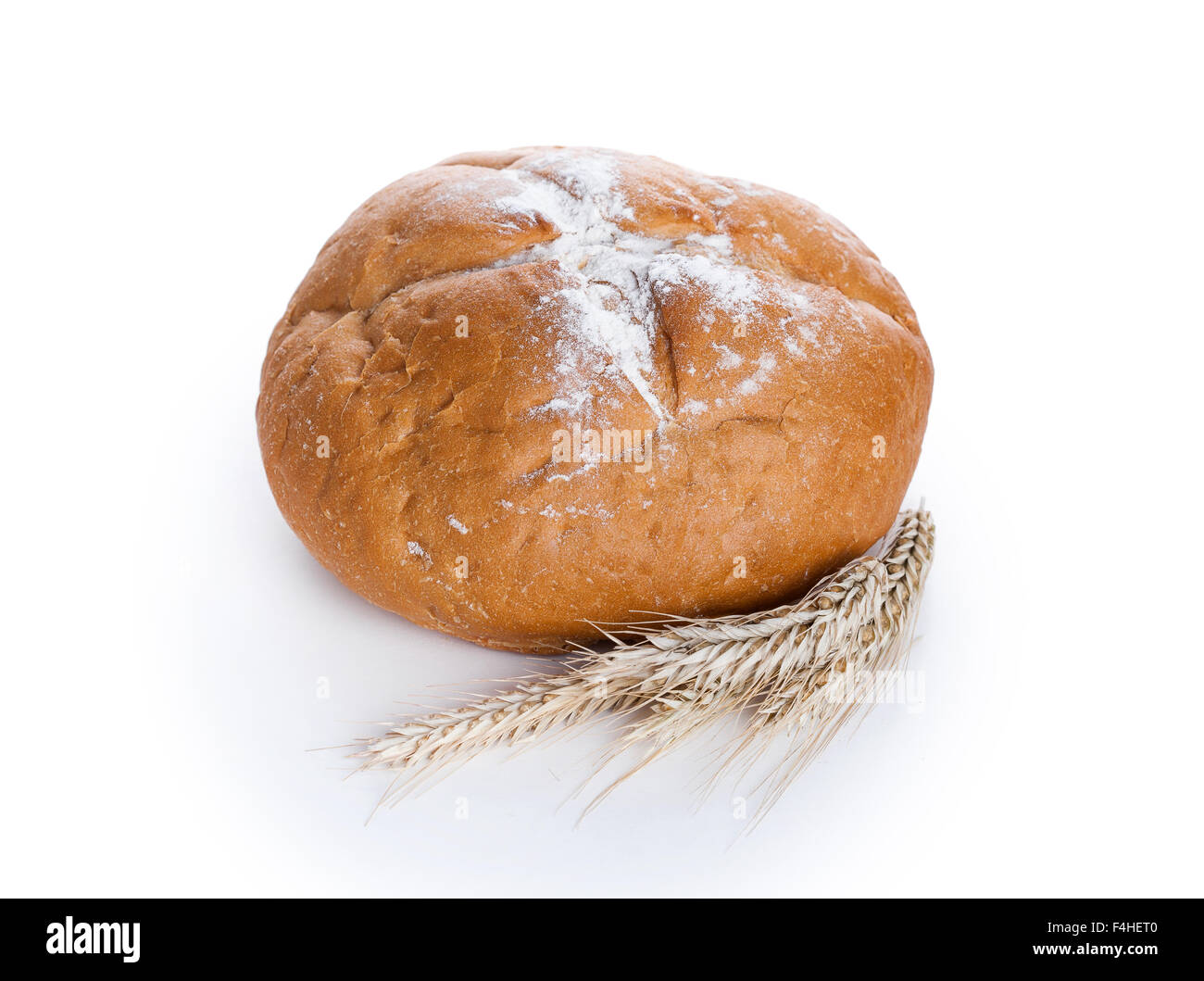 Homemade whole round bread and stalks of wheat on white background ...