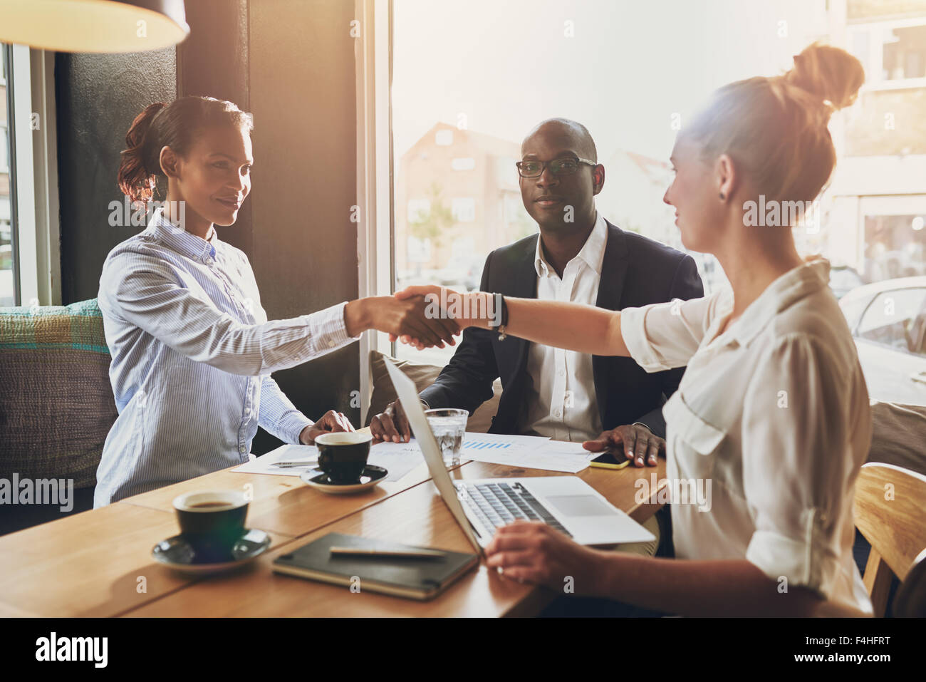 Black business woman and white business woman shaking hands closing a ...