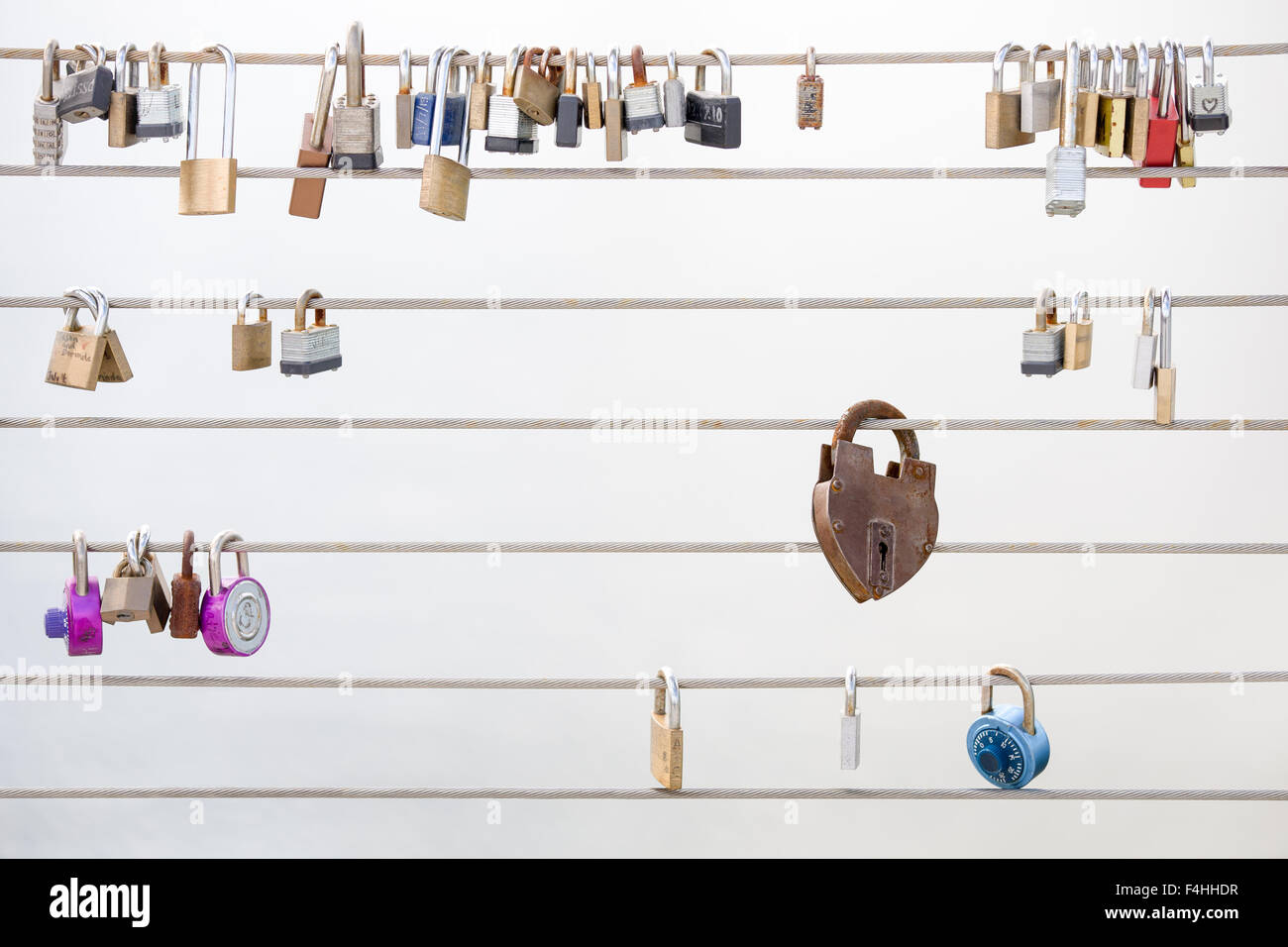 Collection of love locks hanging from a cable bridge railing. One large ...