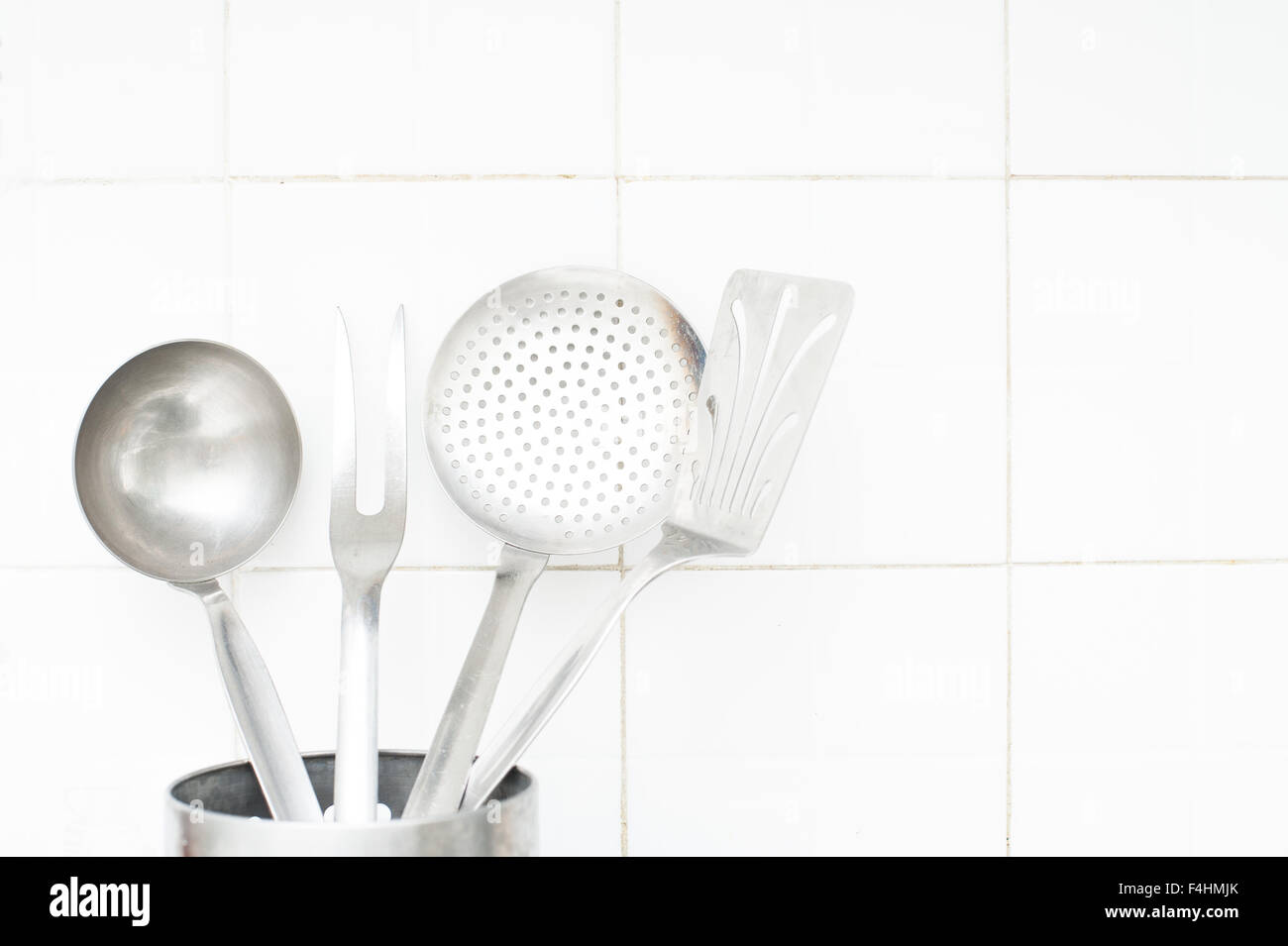Close up of various Steel kitchenwares on white tile wall Stock Photo ...