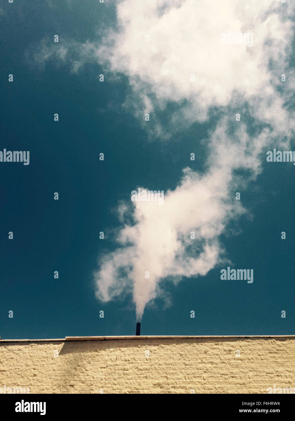 Industrial laundry smokestack spewing white steam cloud vertically up ...