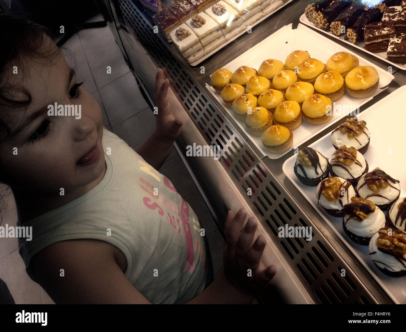 One latin sweet-toothed toddler girl looking sweet in pastry shop Stock ...