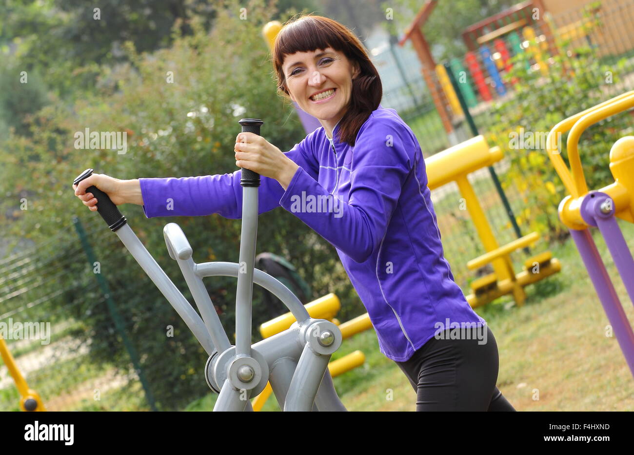 Brunette woman exercising upper body and arms on outdoor gym, concept ...