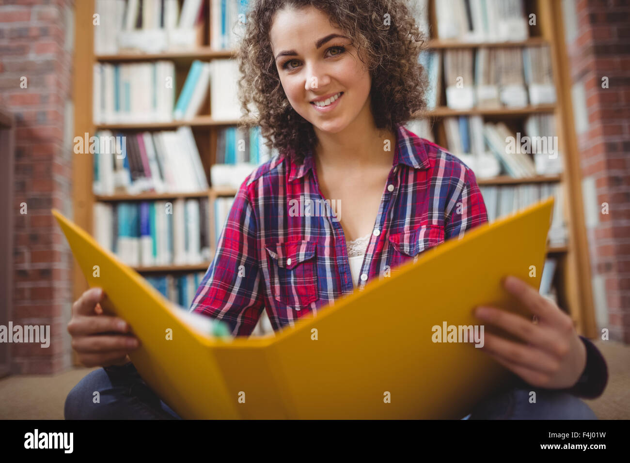 Pretty student in library reading file Stock Photo - Alamy