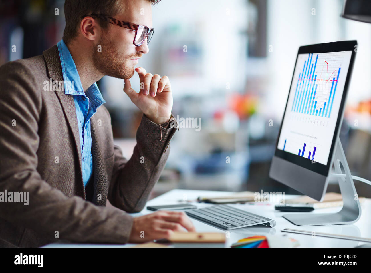 Male office worker looking at computer screen with data Stock Photo - Alamy